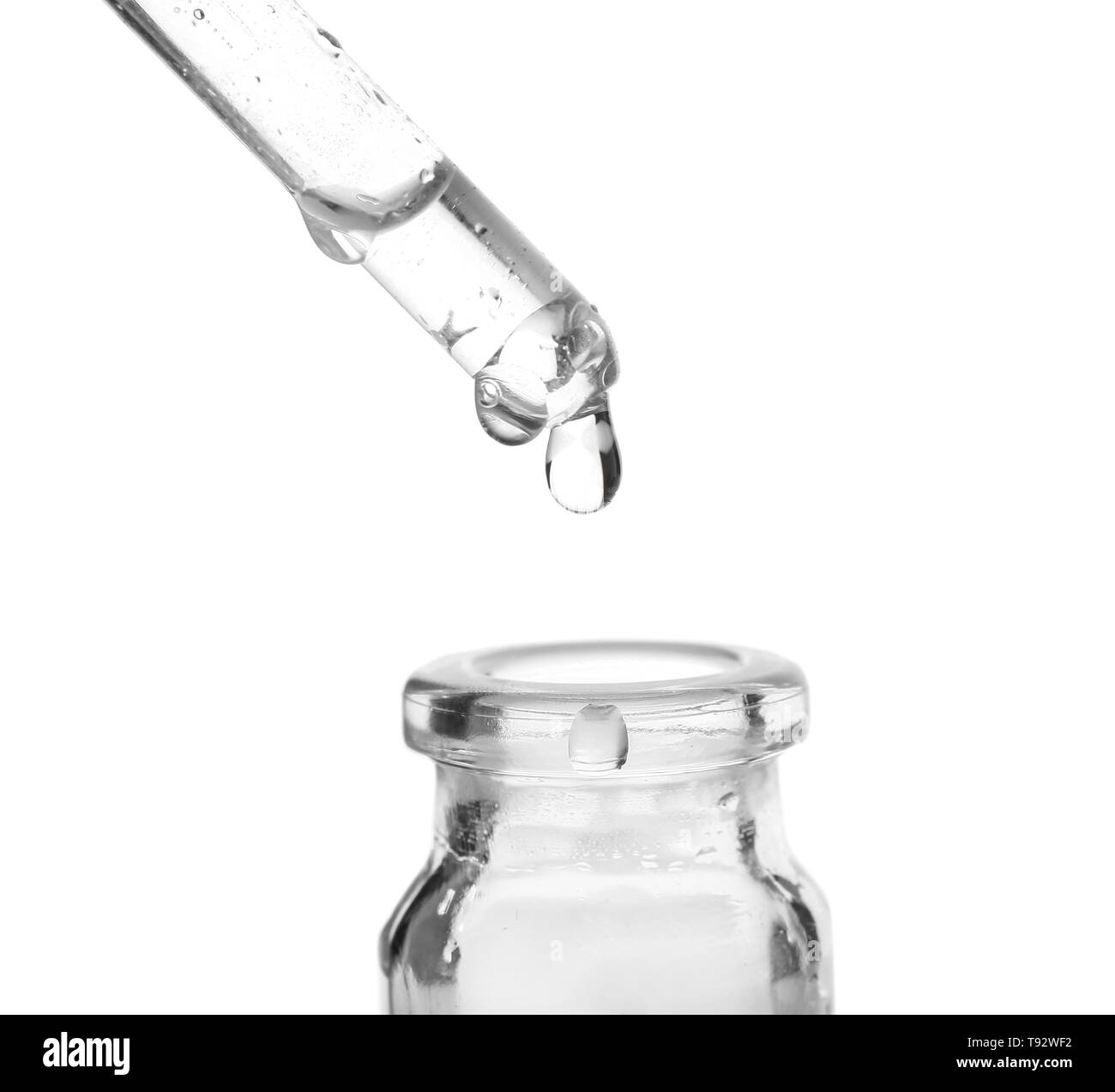 Liquid dripping from pipette into glass bottle on white background ...