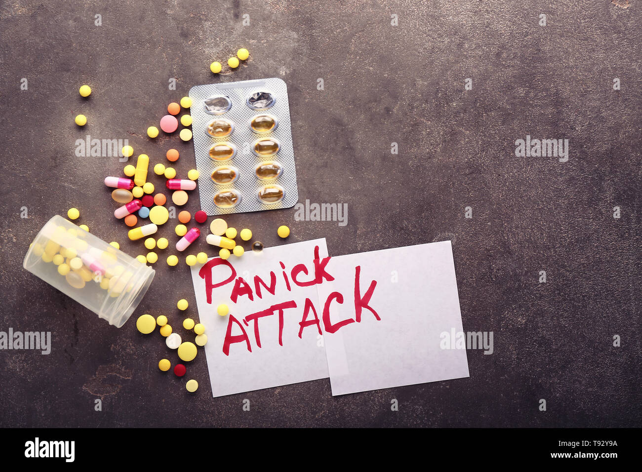 Paper cards with text PANIC ATTACK and scattered pills on grey ...