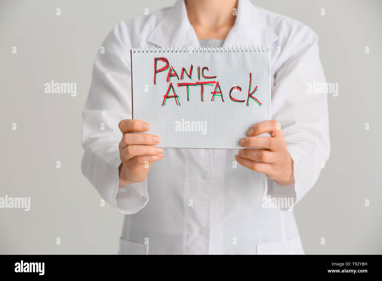 Female doctor holding notebook with written text PANIC ATTACK on white ...