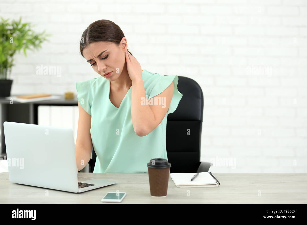 Woman suffering from neck pain while working in office Stock Photo - Alamy