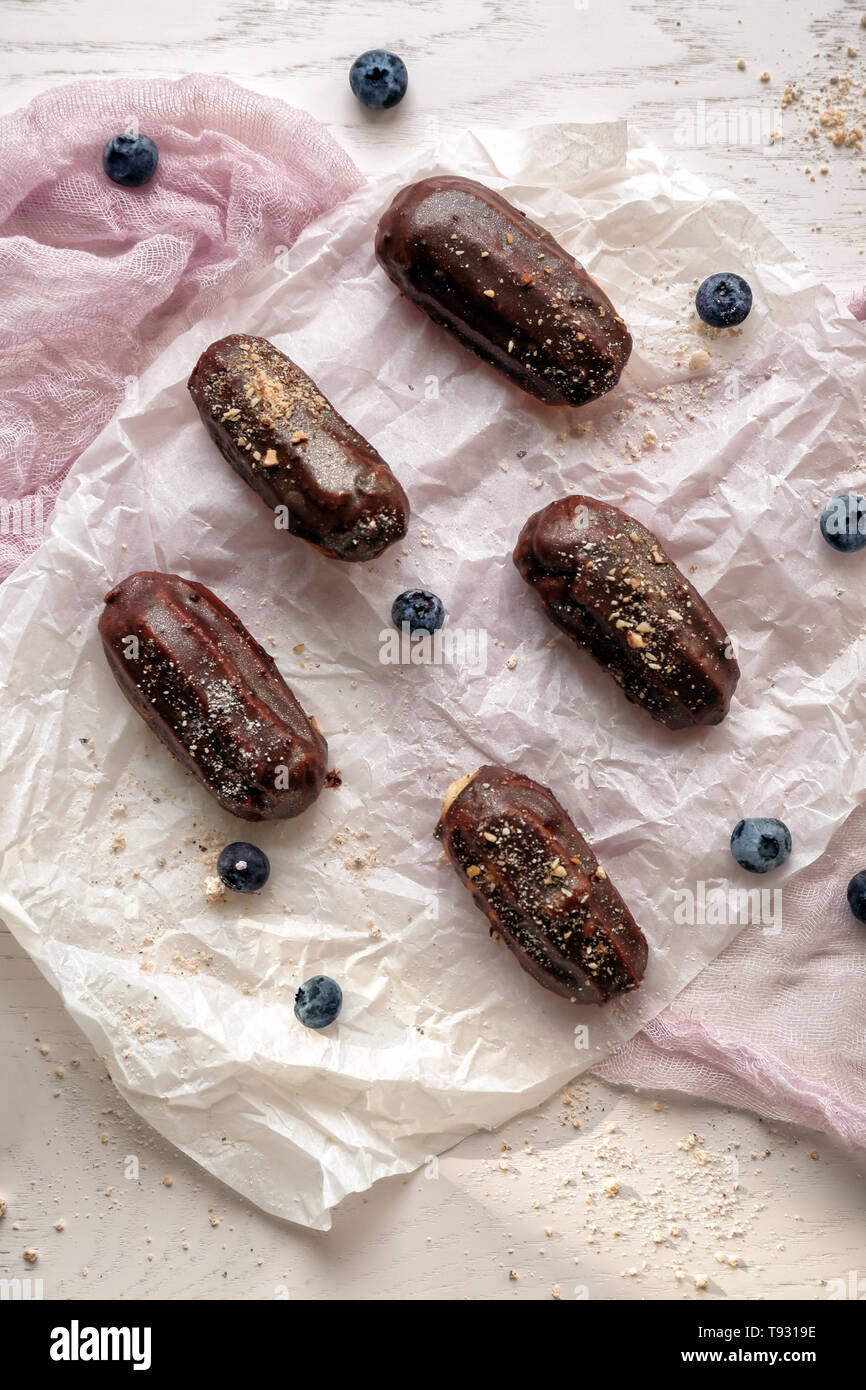 Tasty eclairs with blueberries on parchment Stock Photo - Alamy