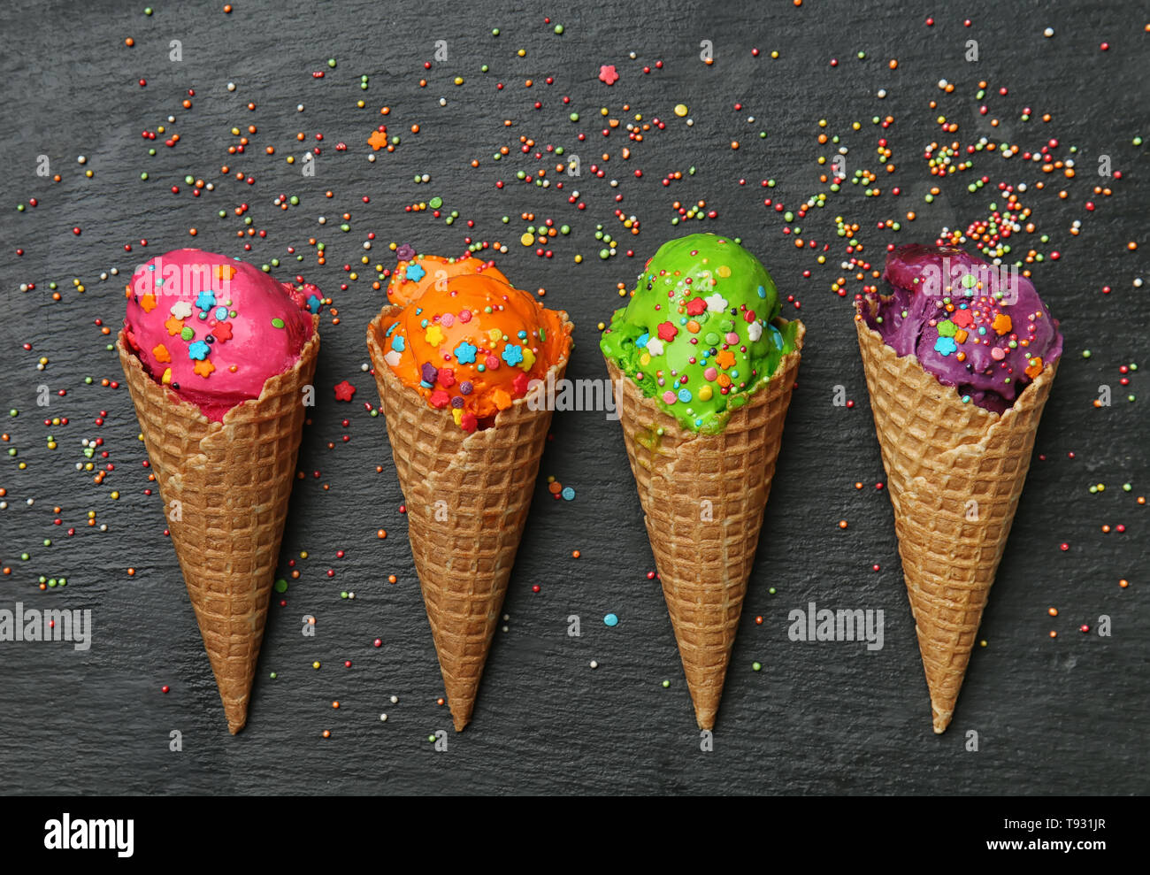Waffle cones with delicious color ice cream and sprinkles on dark ...