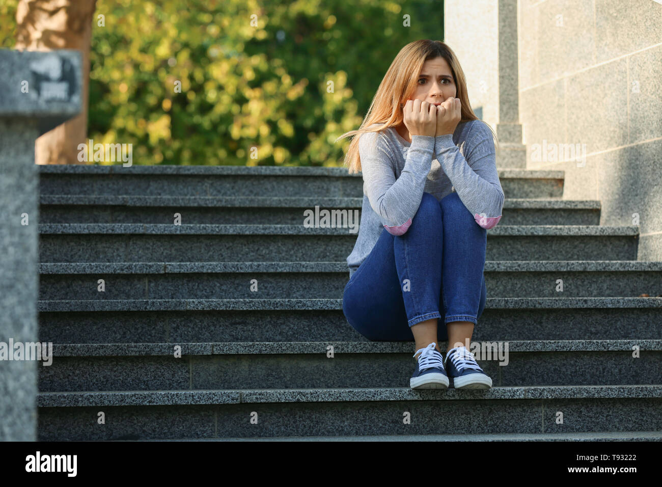 Woman having panic attack while sitting on steps outdoors Stock Photo ...