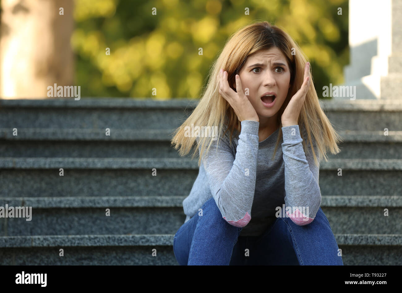 Woman having panic attack while sitting on steps outdoors Stock Photo ...