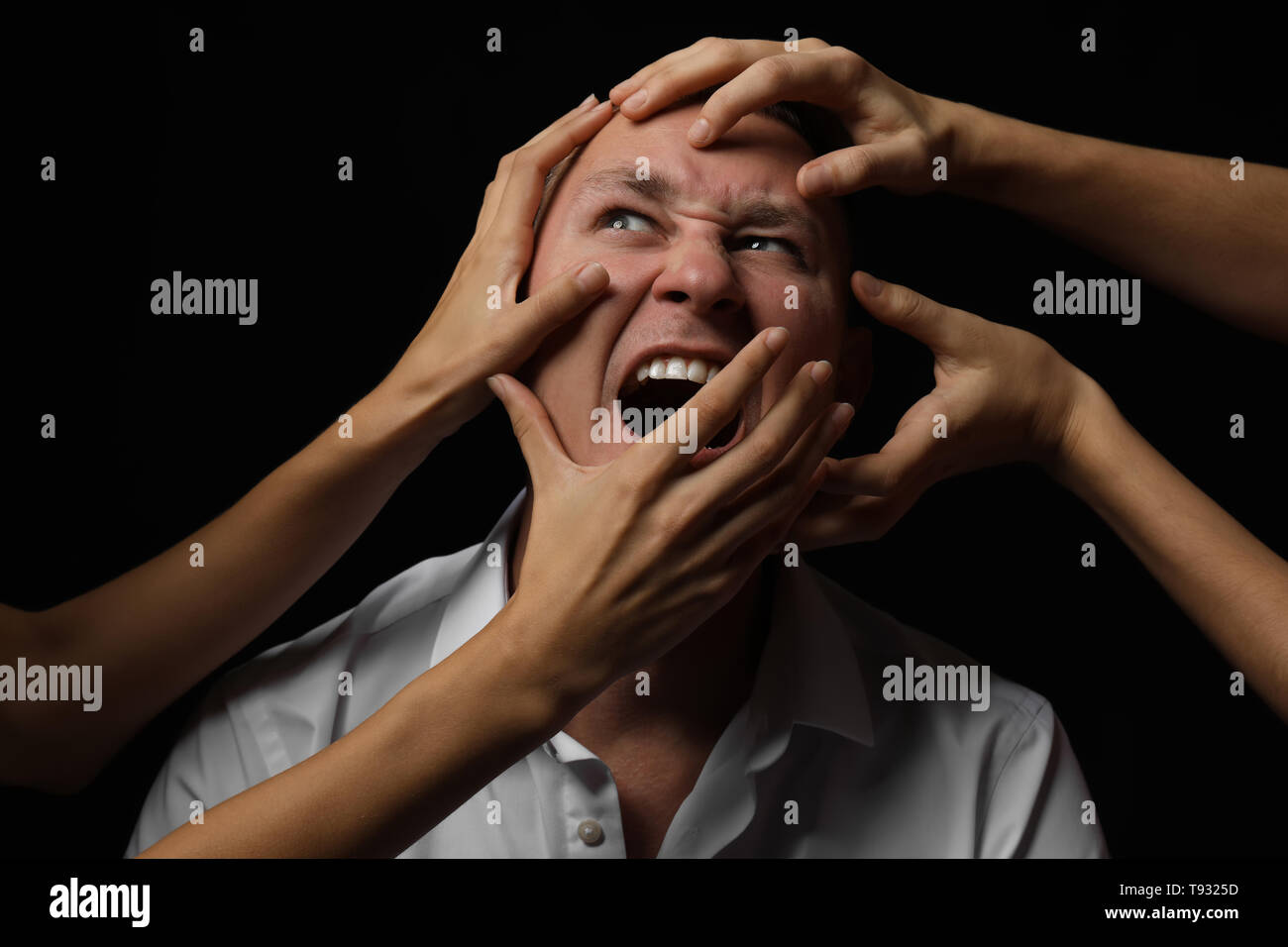 Many hands stretched to man on dark background. Panic attack Stock ...