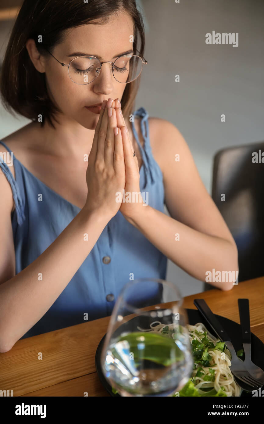 Young woman praying before meal at home Stock Photo - Alamy