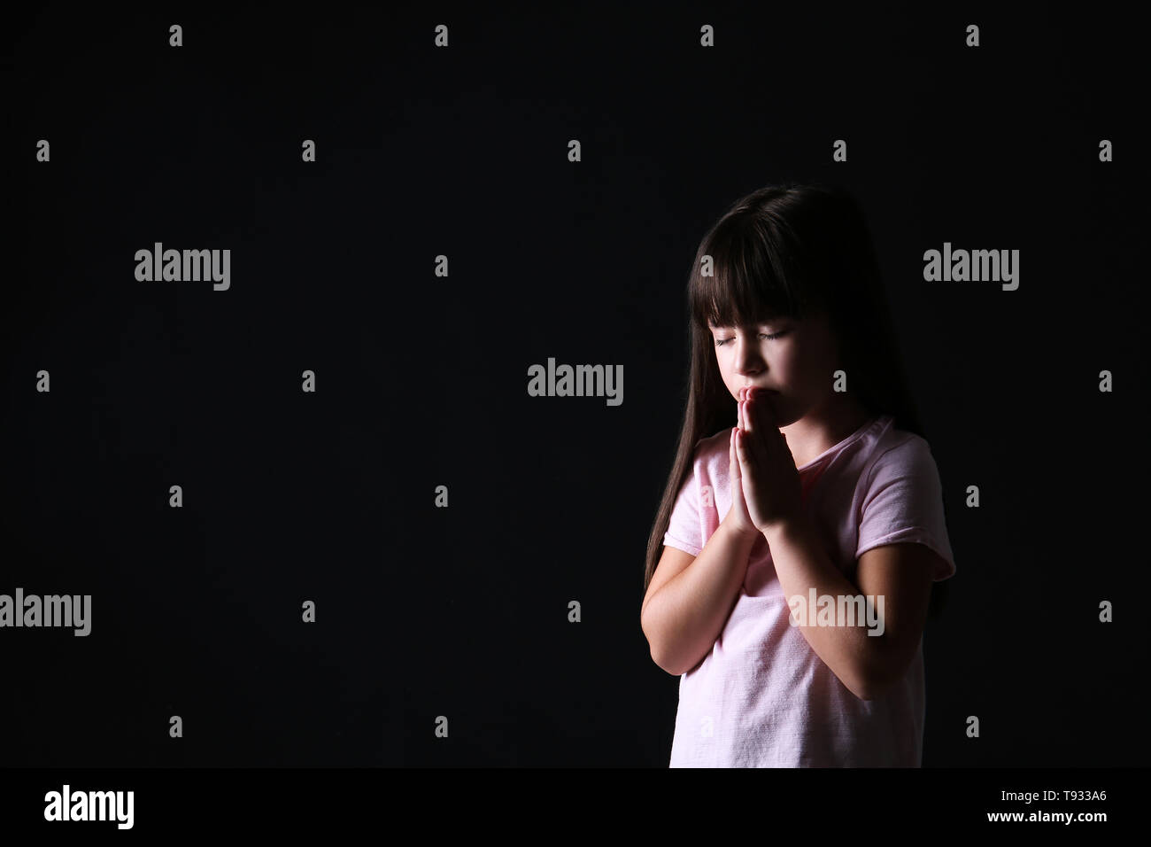 Portrait of praying girl on dark background Stock Photo - Alamy