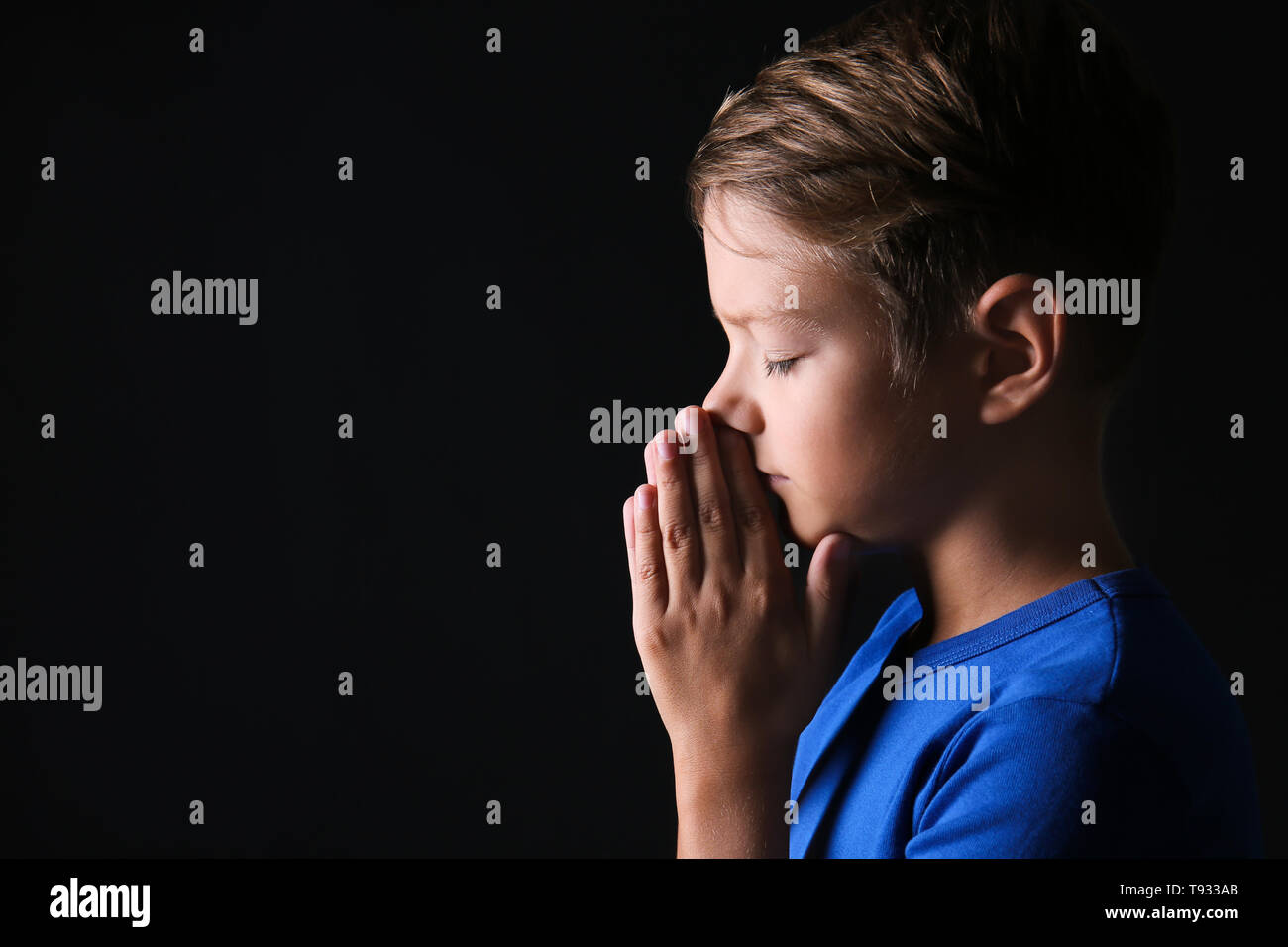 Portrait of praying boy on dark background Stock Photo - Alamy