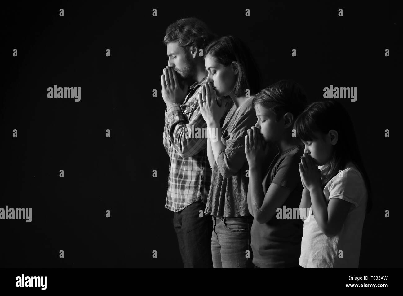 Praying family on dark background Stock Photo - Alamy