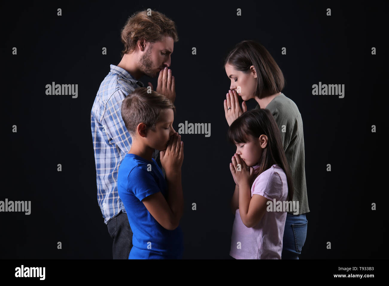Praying family on dark background Stock Photo - Alamy