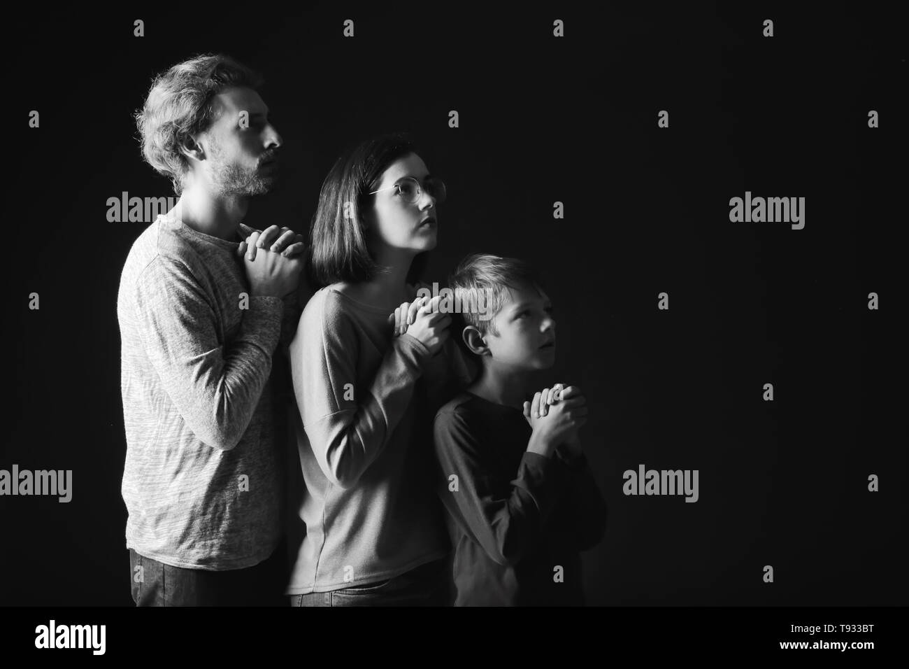Praying family on dark background Stock Photo - Alamy