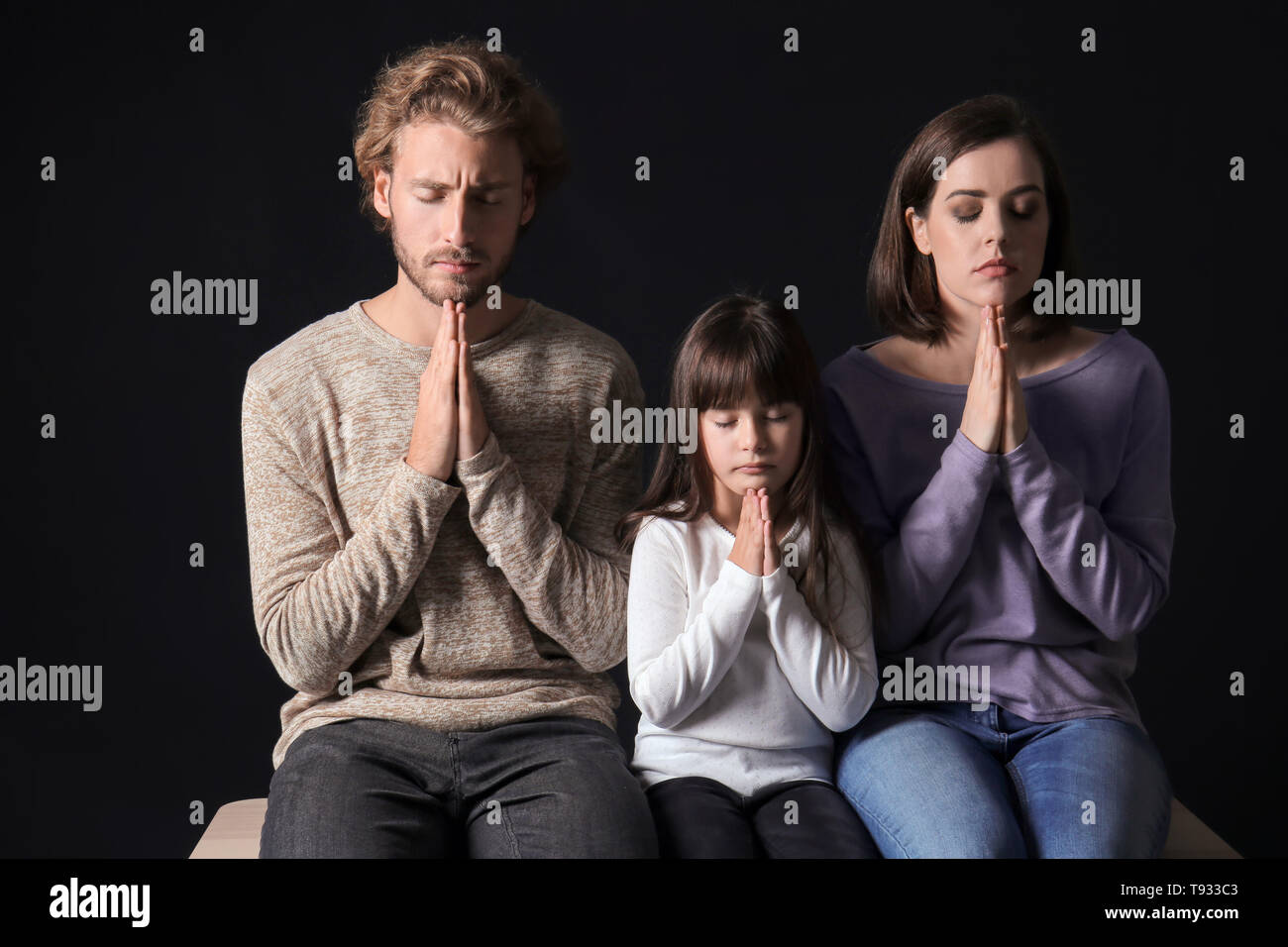 Praying family on dark background Stock Photo - Alamy