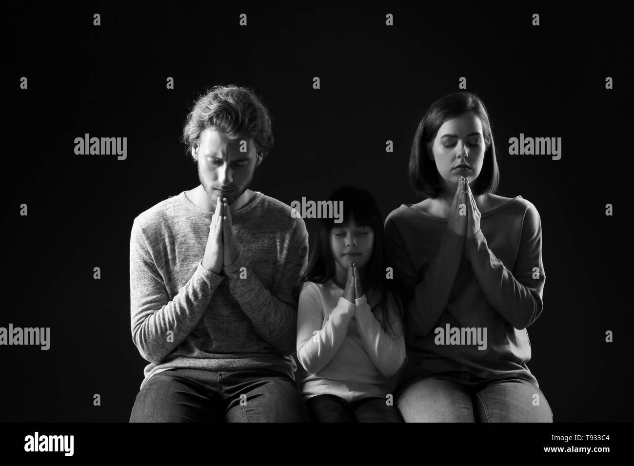 Praying family on dark background Stock Photo - Alamy