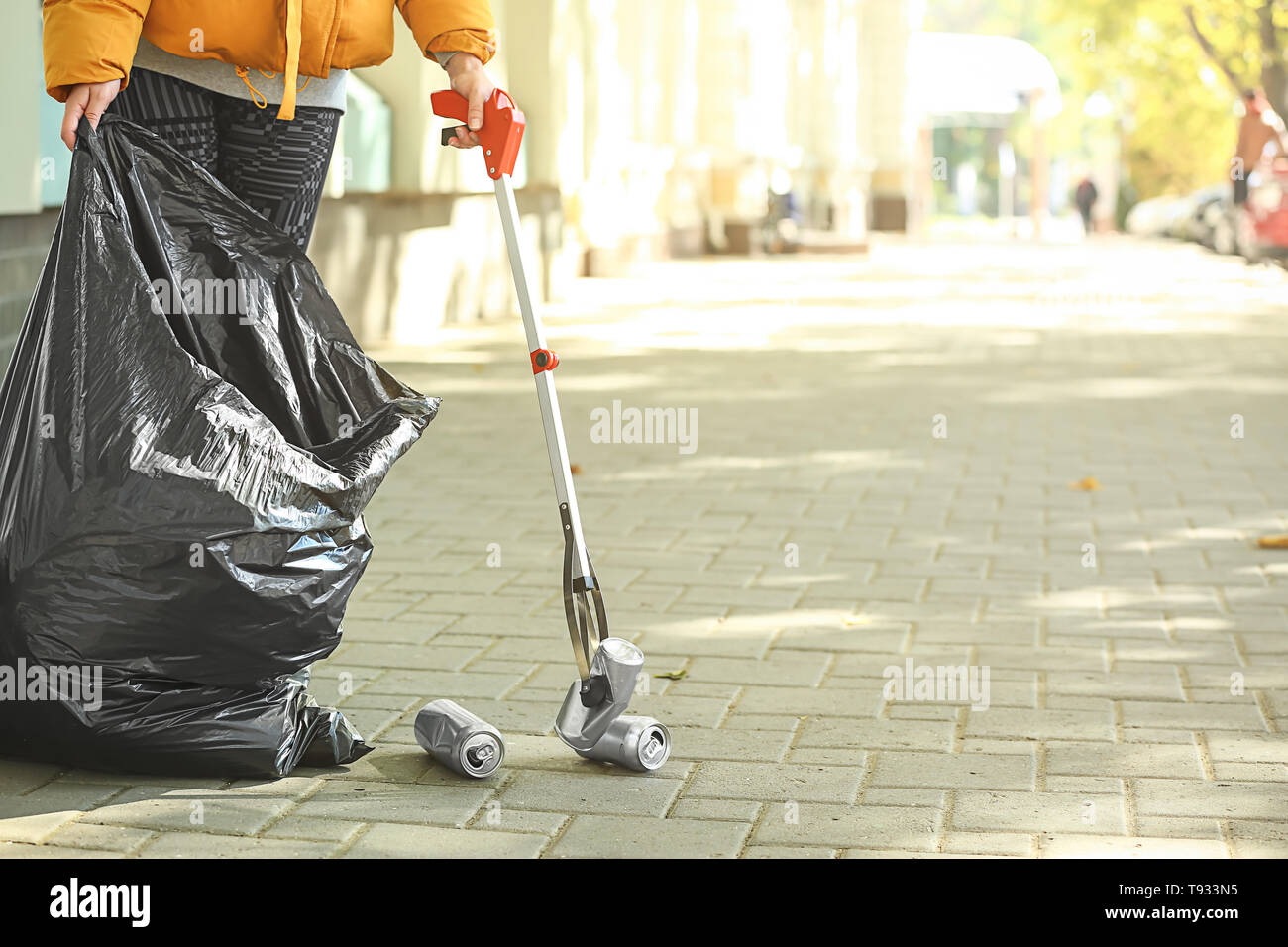 Woman gathering trash on city street Stock Photo - Alamy