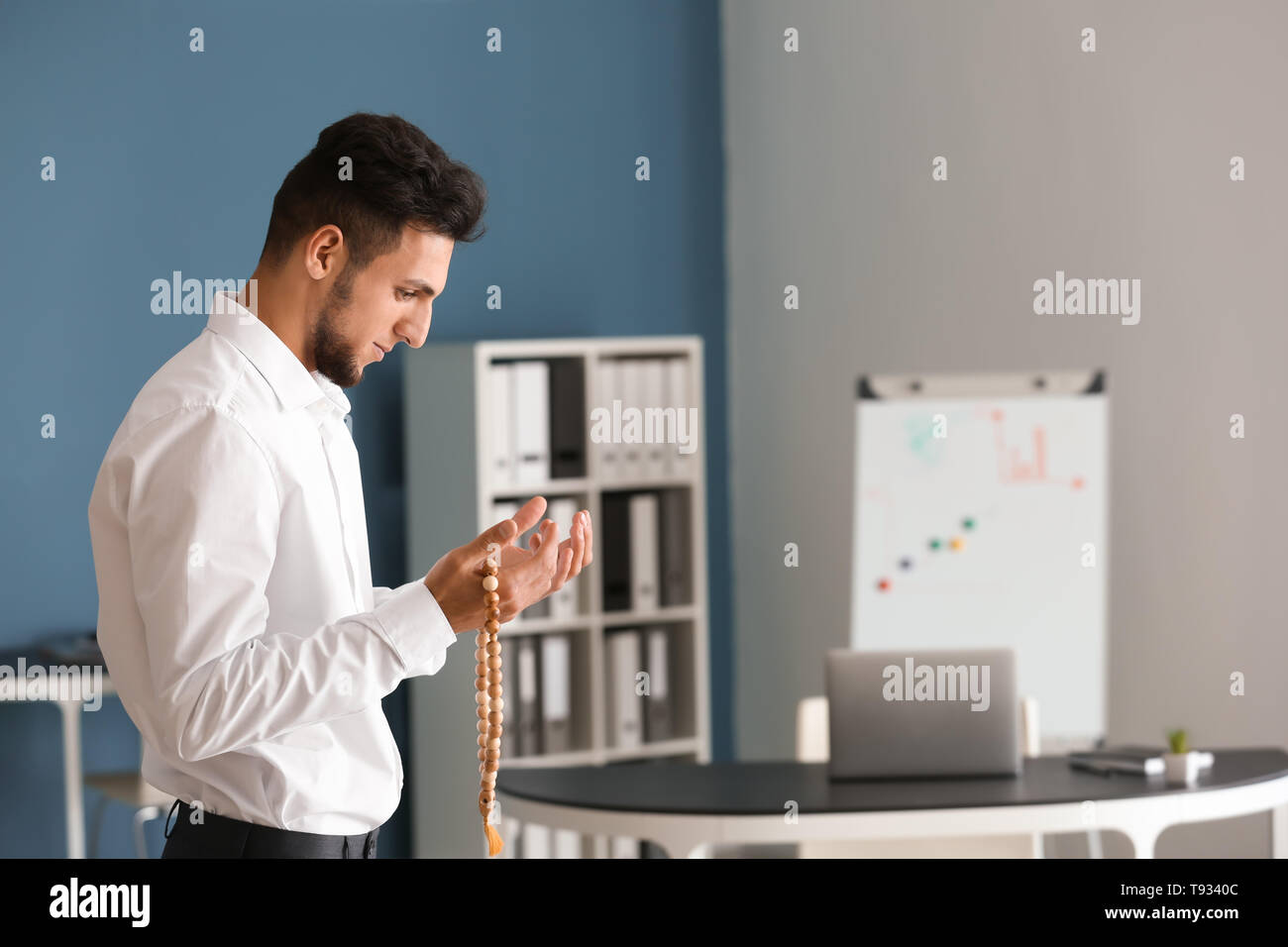 Young Muslim man praying in office Stock Photo - Alamy