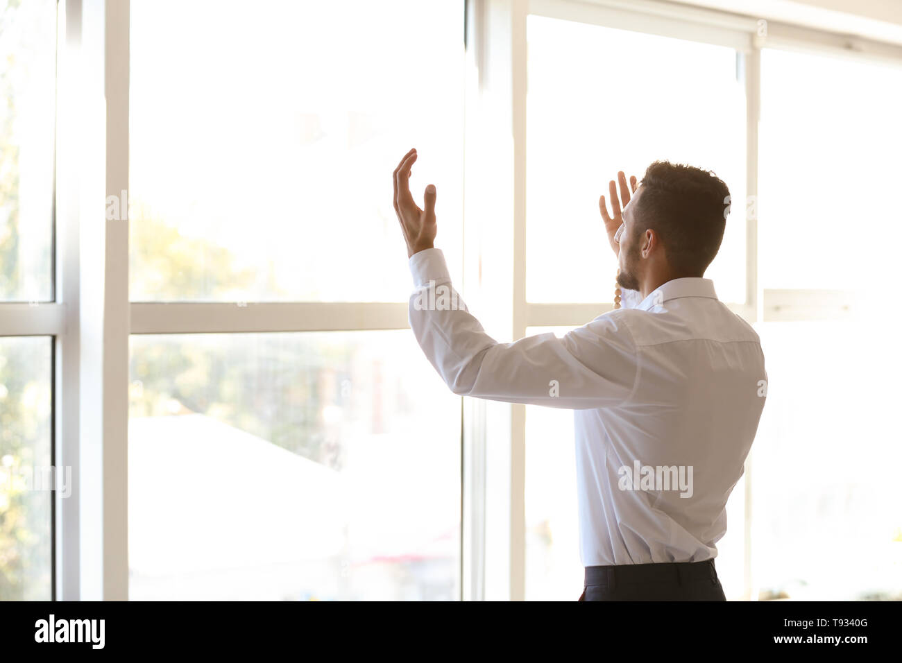 Young Muslim man praying near window Stock Photo - Alamy