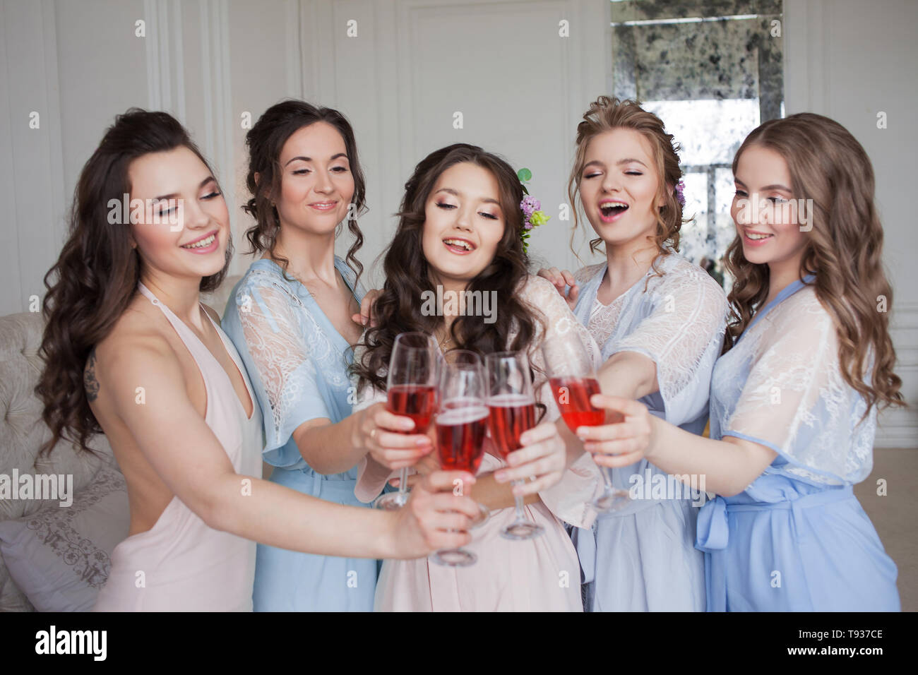 Cheerful young women raise a toast and clink glasses. Birthday or ...