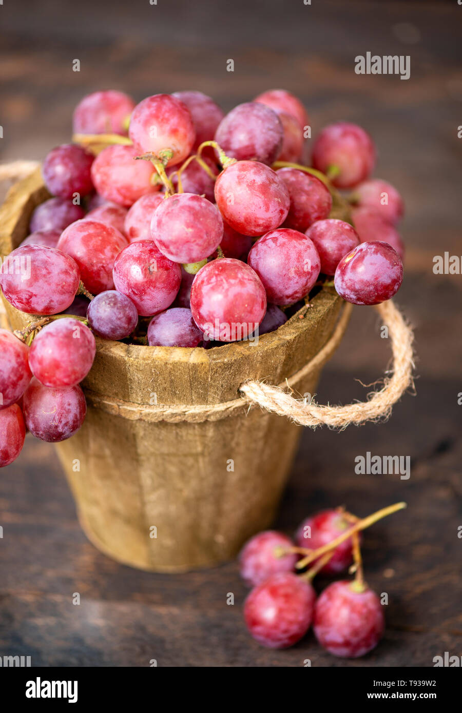 Rose grapes in wooden bucket on a woden table Stock Photo - Alamy