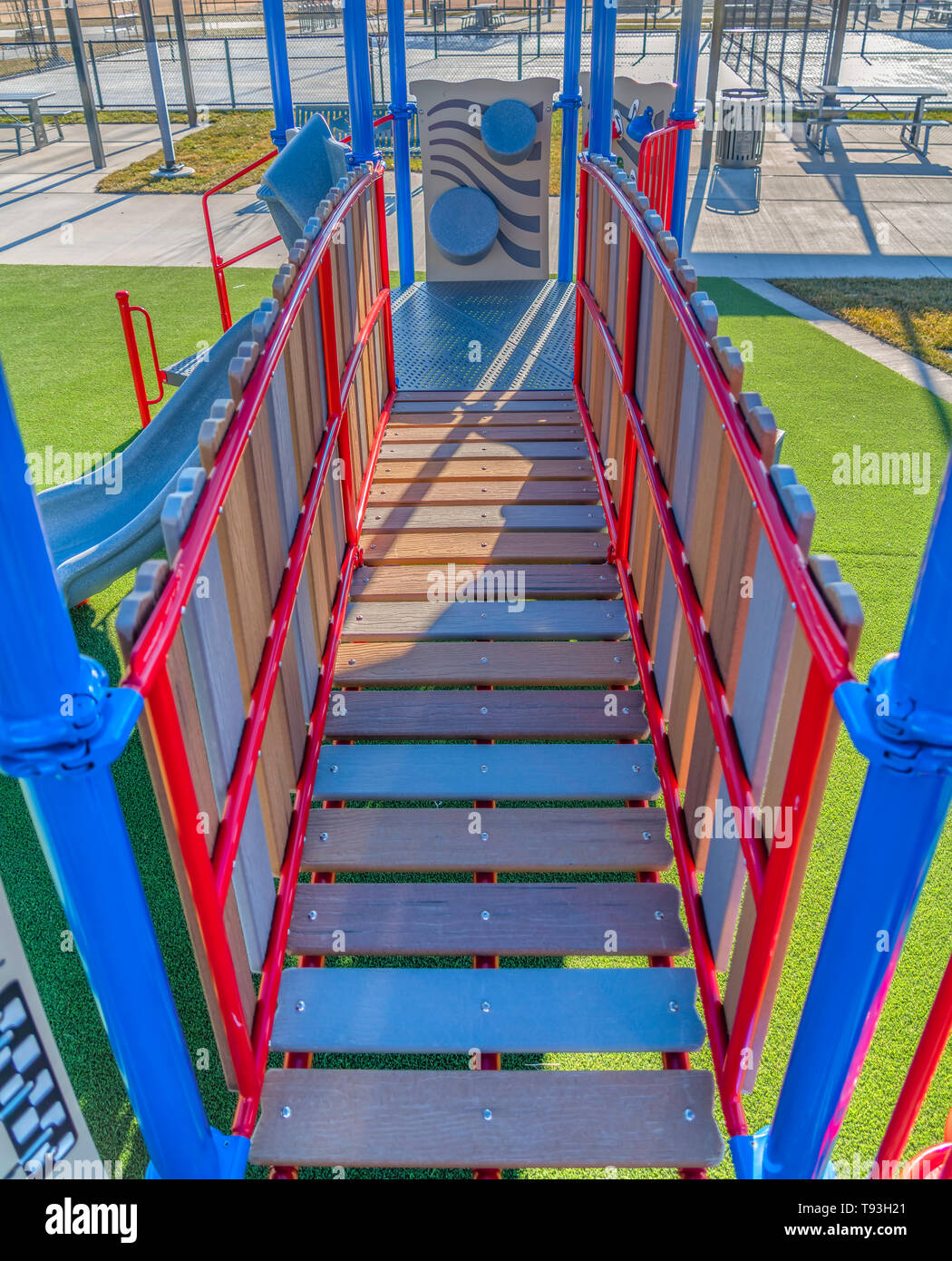 Playground equipment with a bridge and slide against vibrant green lawn ...