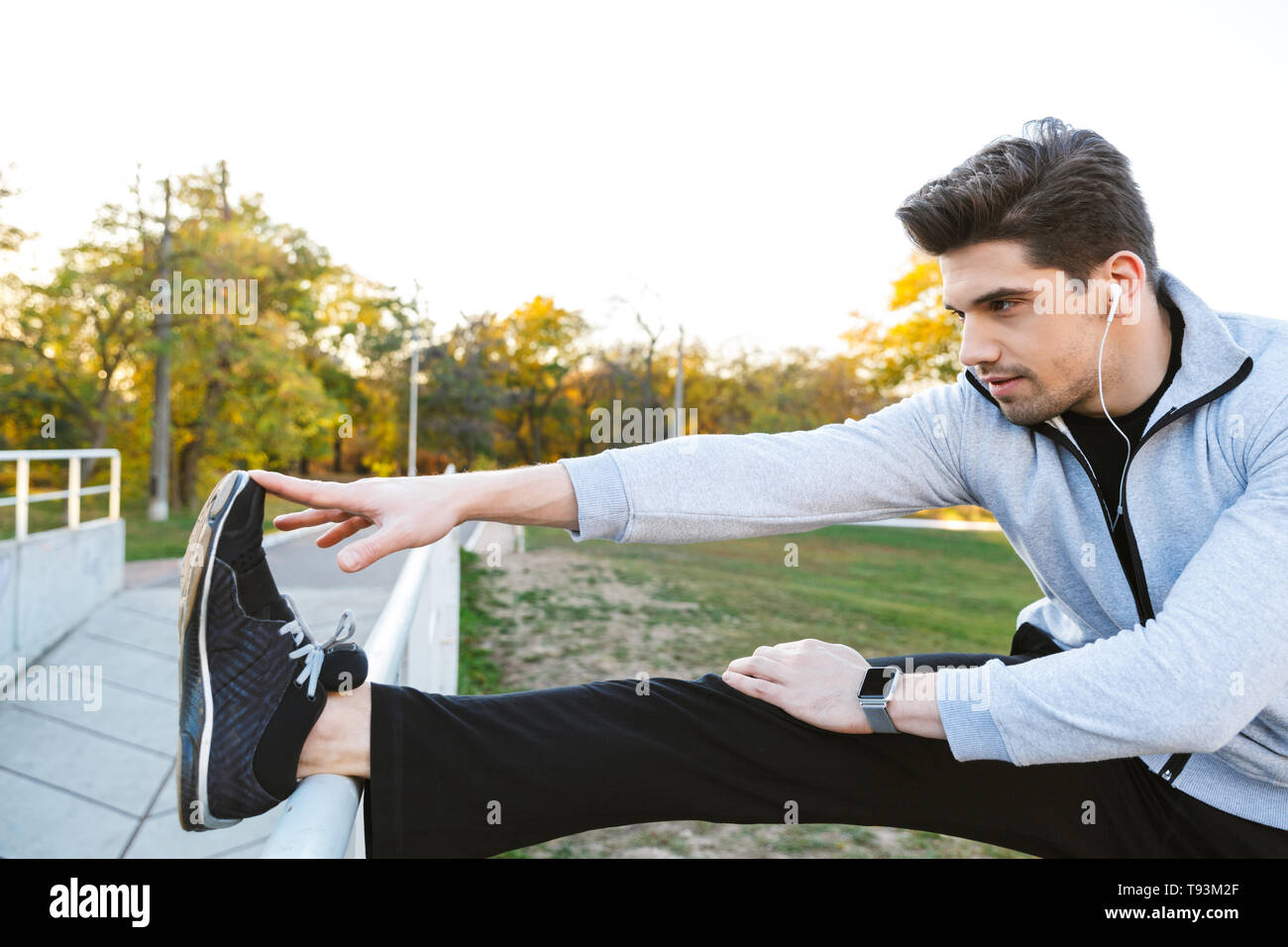 Confident healthy sportsman doing stretching exercises outdoors ...