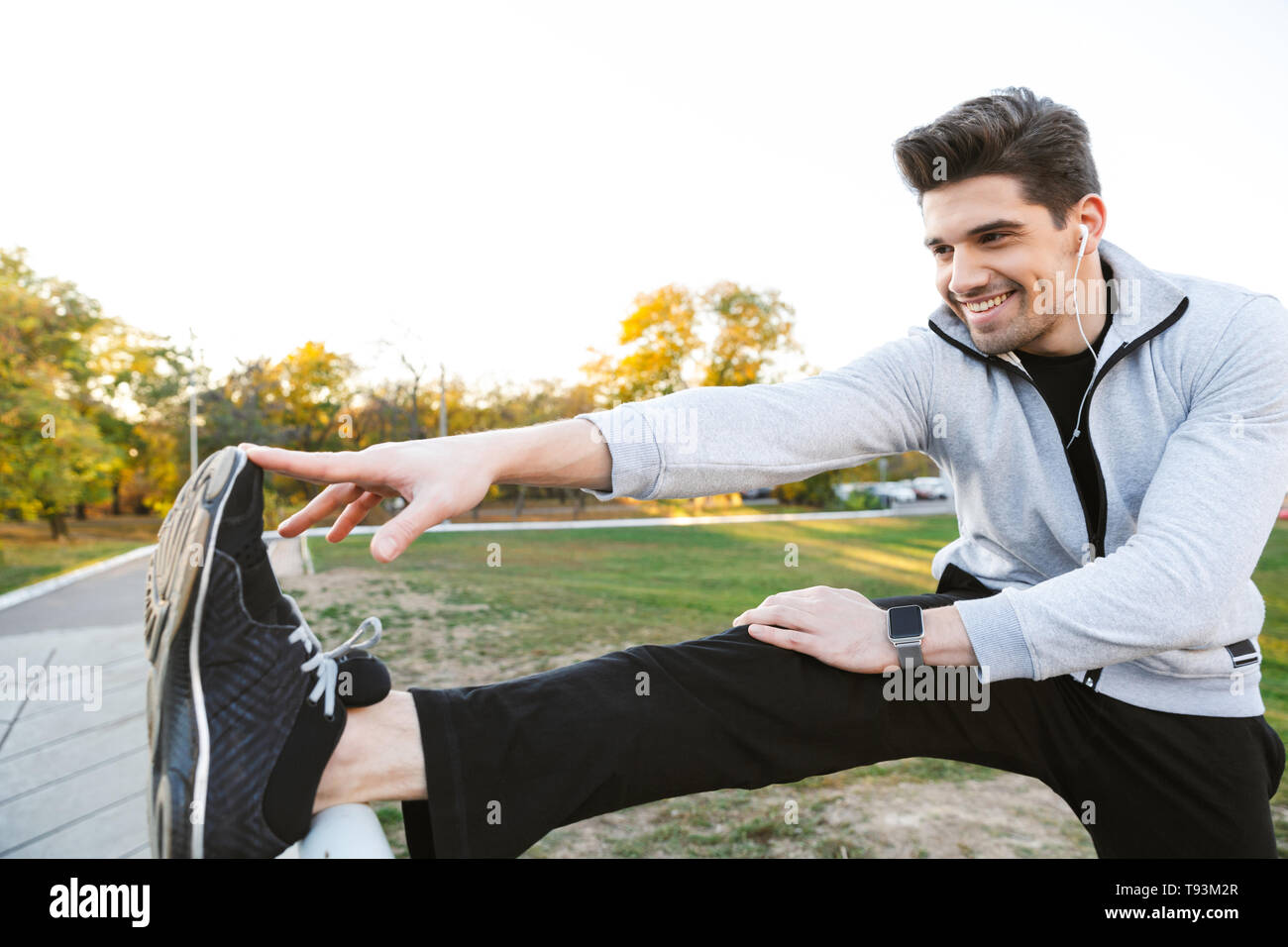 Confident healthy sportsman doing stretching exercises outdoors ...
