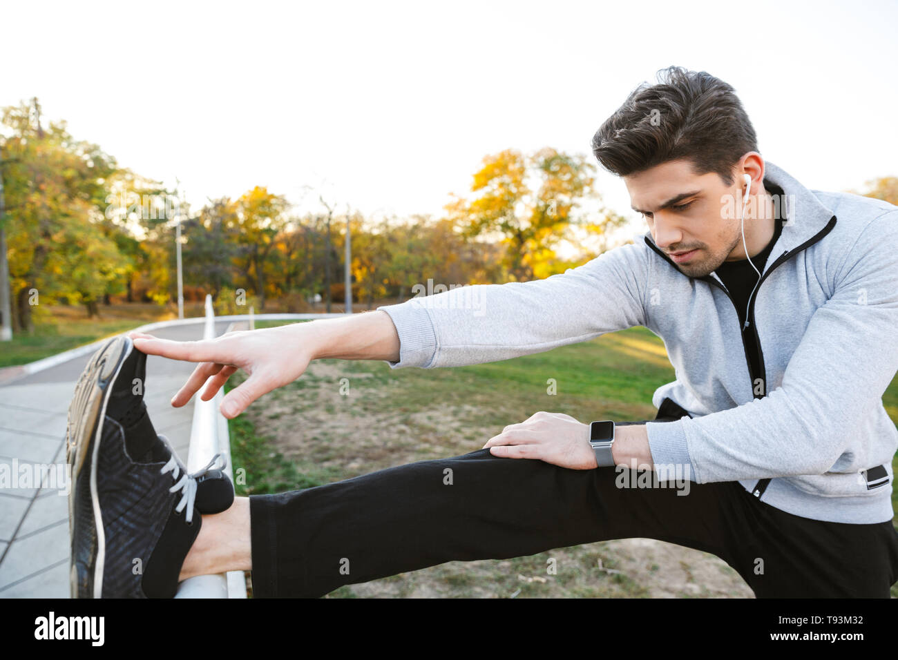 Confident healthy sportsman doing stretching exercises outdoors ...