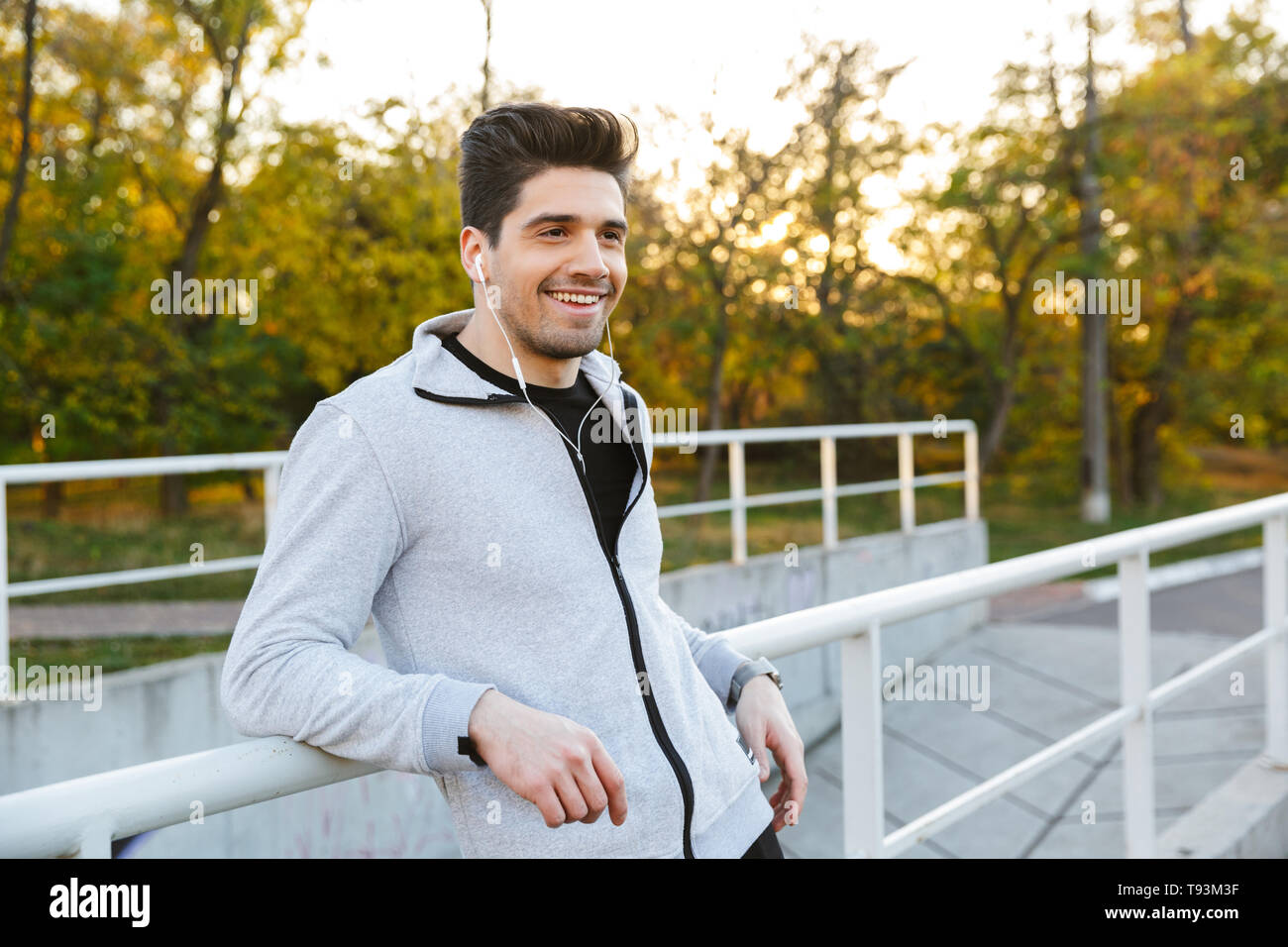Smiling healthy sportsman standing outdoors at the railing Stock Photo ...