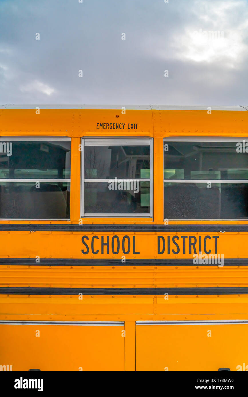 CLose up of the exterior of a yellow school bus against cloudy sky ...