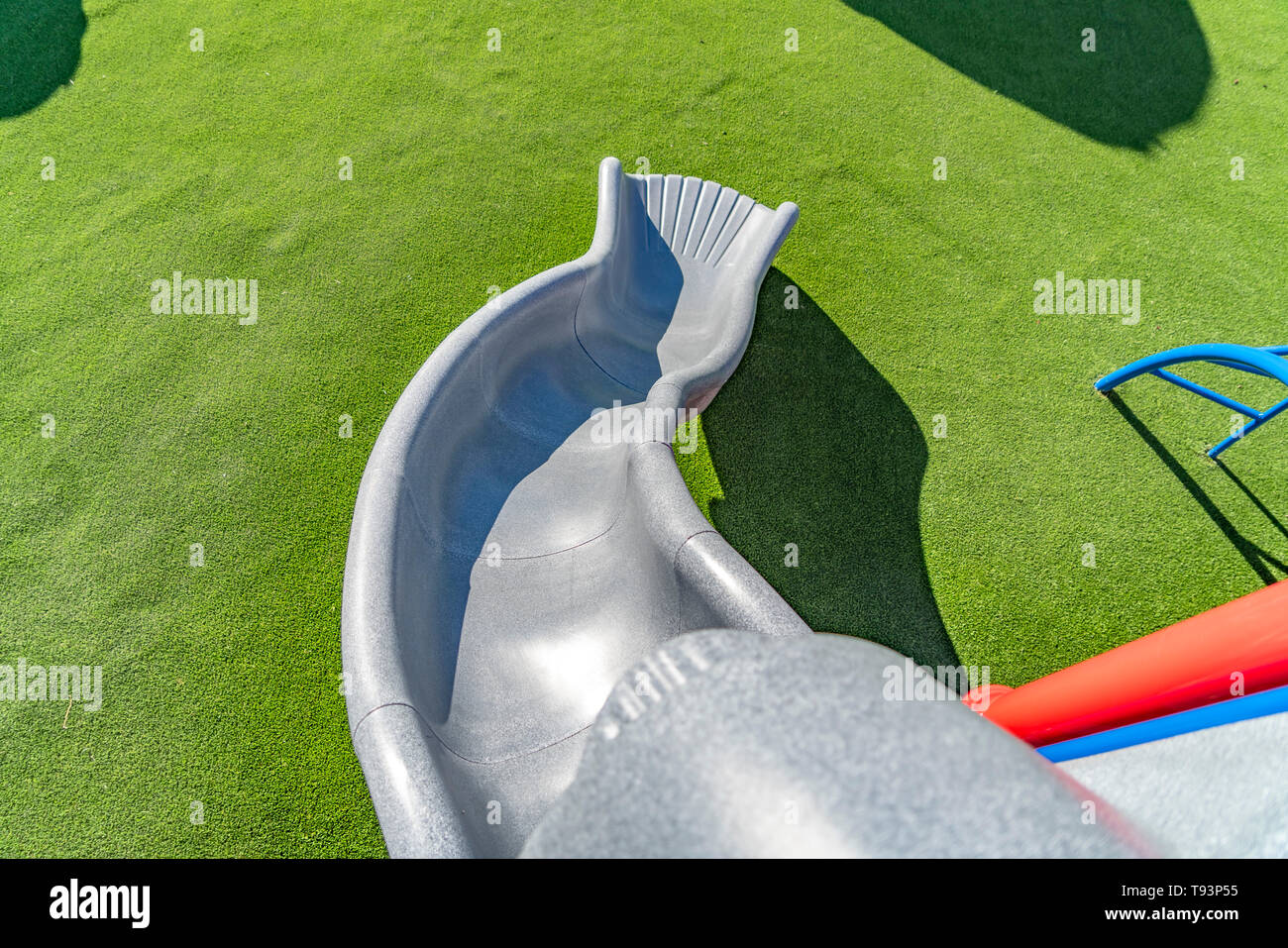 Playground with smooth and shiny gray slide against a vibrant green ...