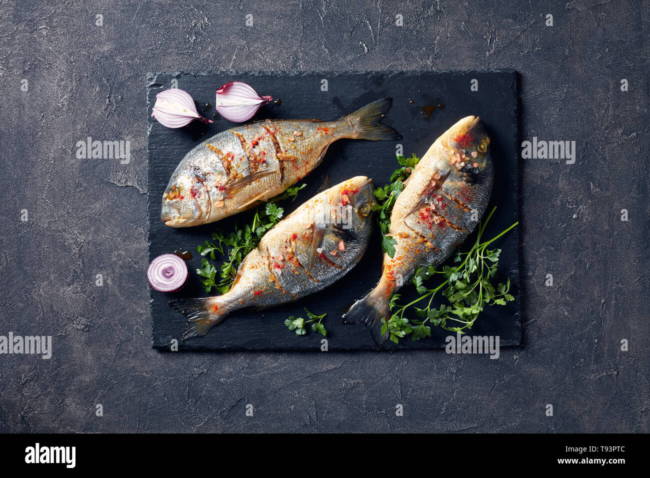 three Raw dorado fish prepared to cook with spices, sea salt, parsley ...