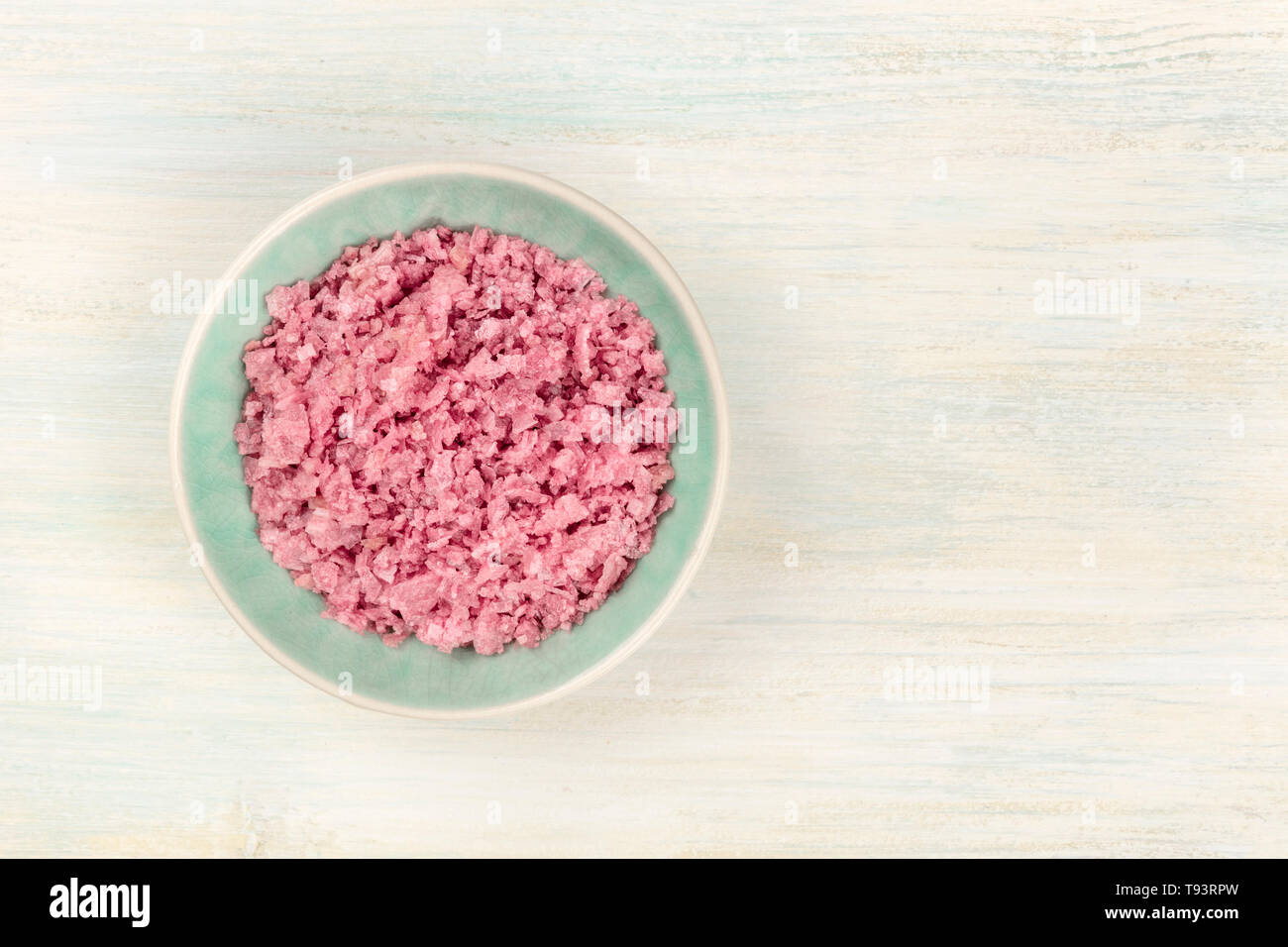 A bowl of pink Himalayan sea salt, shot from the top on a white wooden ...