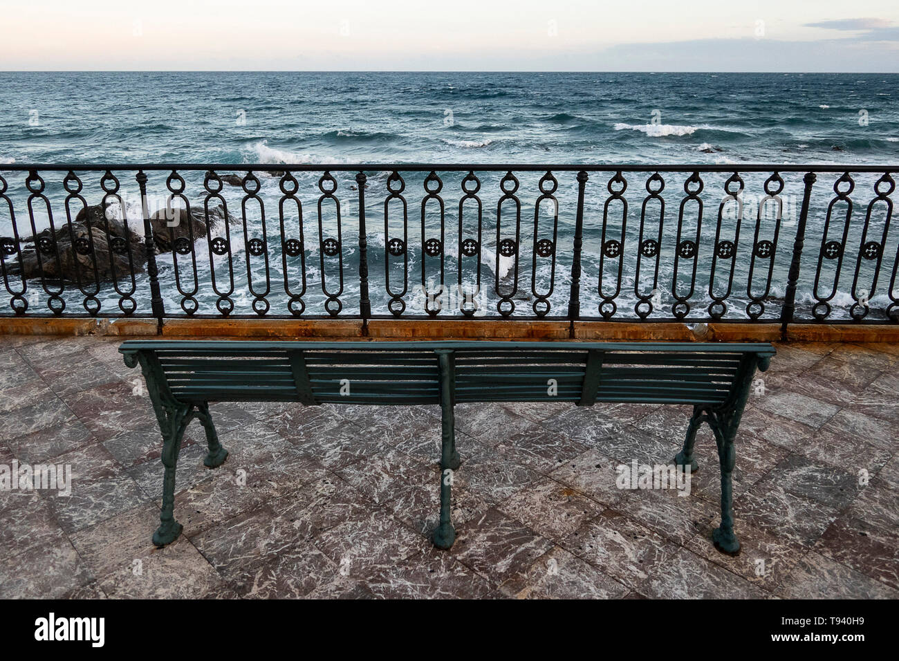Bench facing the sea and waves in Giardini Naxos, Mediterranean coast ...