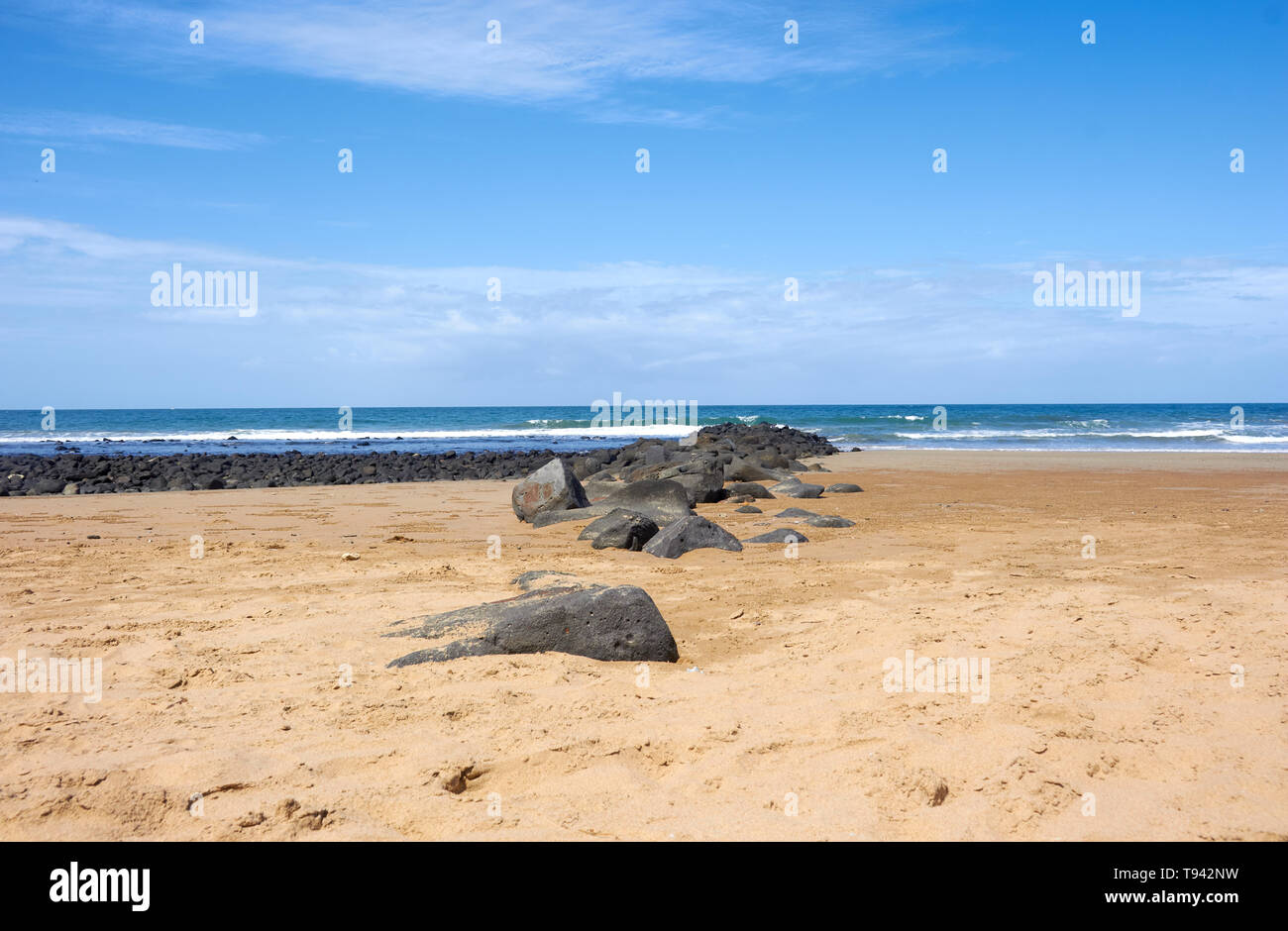 Sandy beach with rocks by the surf on a summer day Stock Photo - Alamy