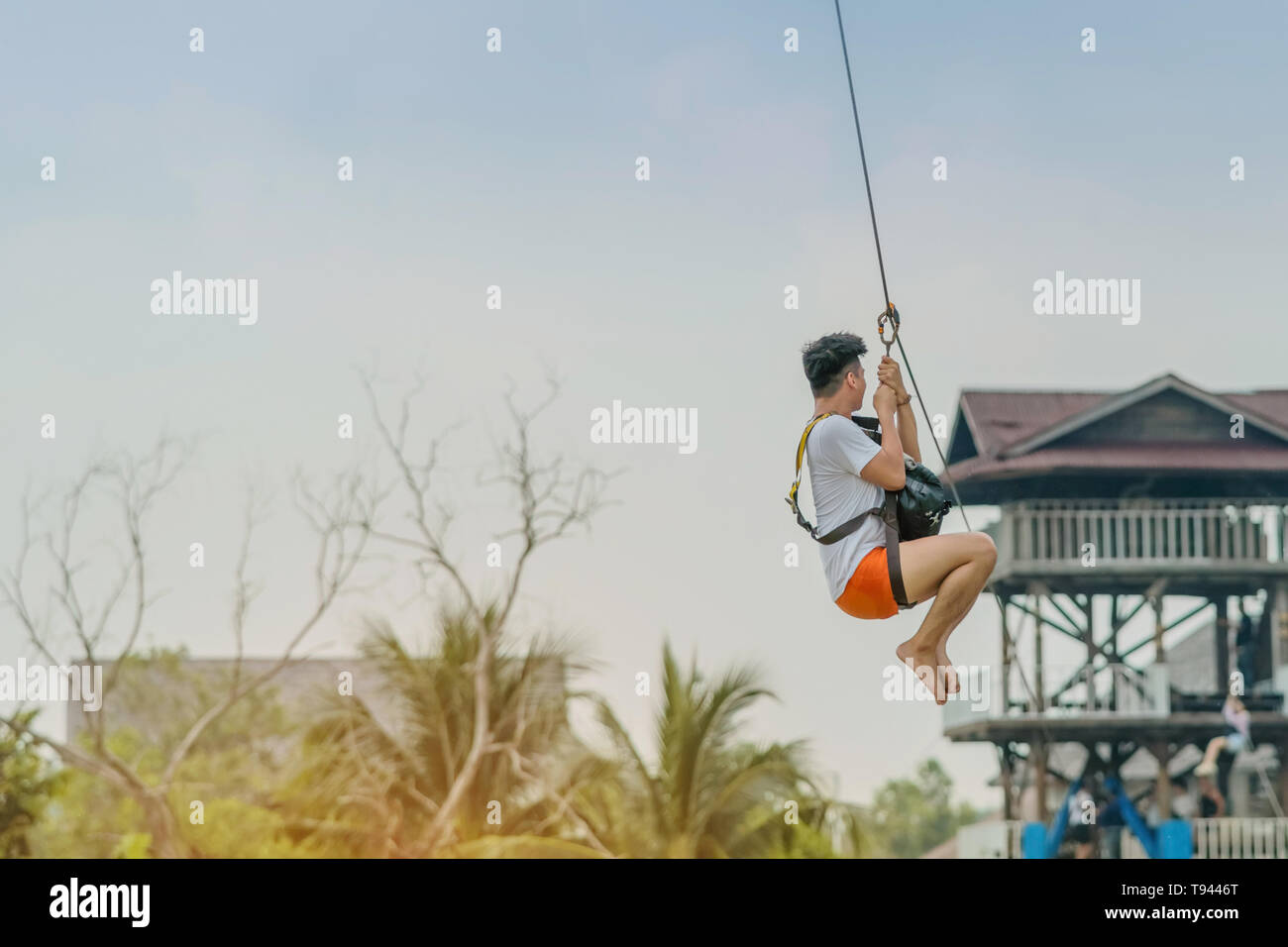 A male tourist flying on a zipline aka flying fox across the lake at ...
