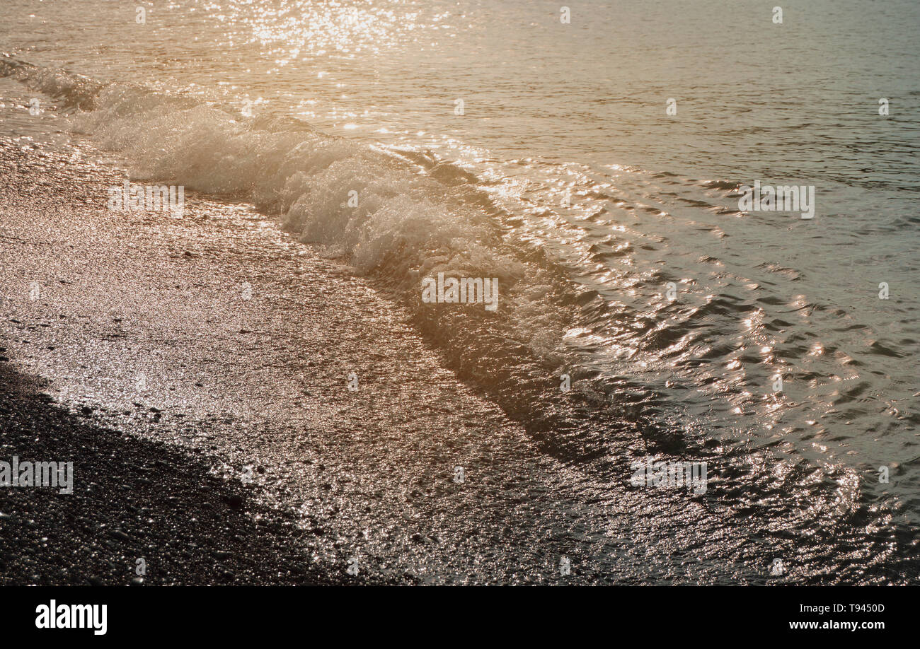 Shiny silver water on the sea pebble beach, early morning sunrise Stock ...