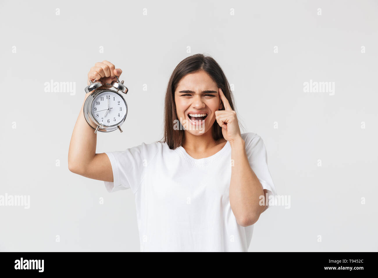 Angry young girl standing isolated over white background, showing alarm ...