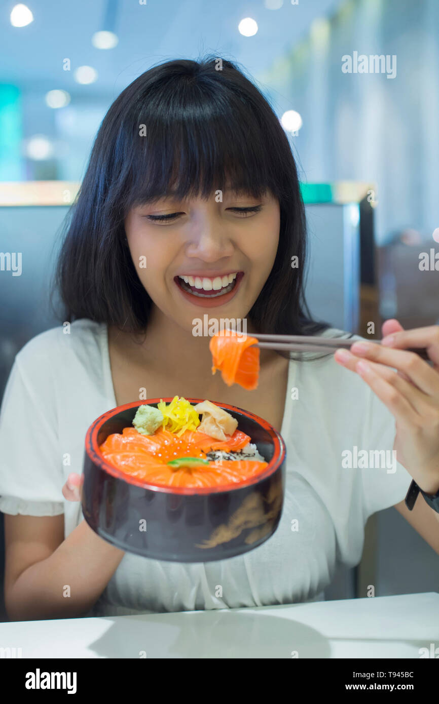 Portrait of smiling young asian woman eating japanese food in ...