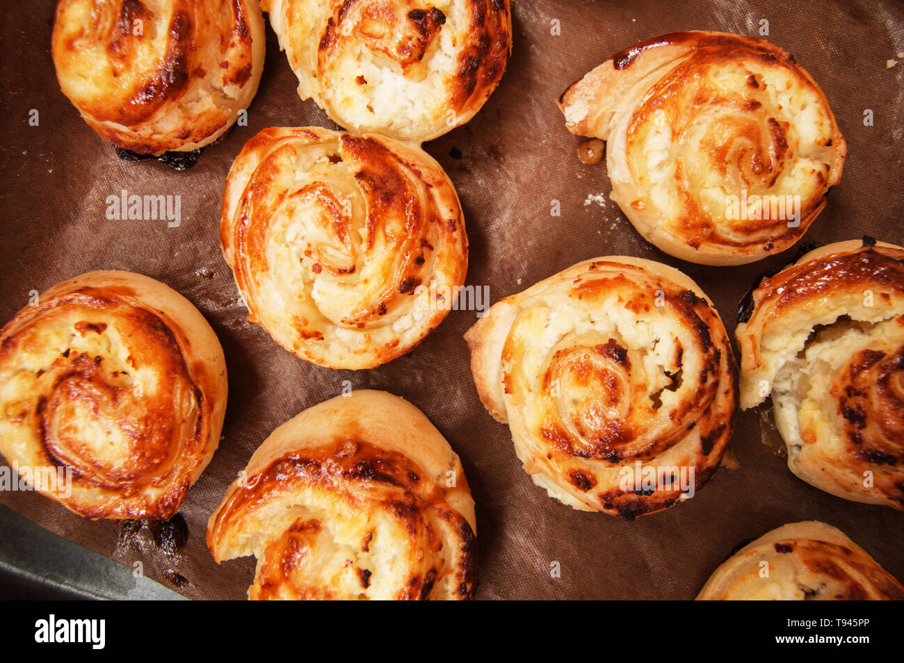Fresh sweet homemade buns twisted in rolls on parchment paper. Top view ...