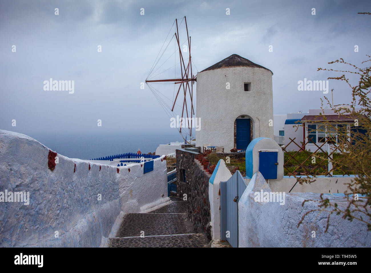 Windmill in the colorful village of Oia on a rainy day Stock Photo - Alamy