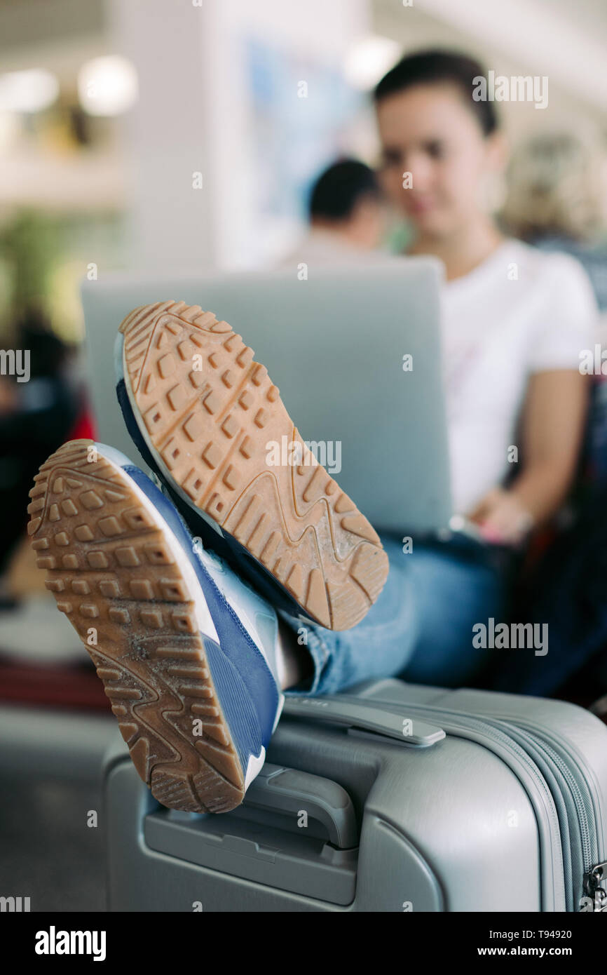 Young female passenger using laptop computer at airport while waiting ...