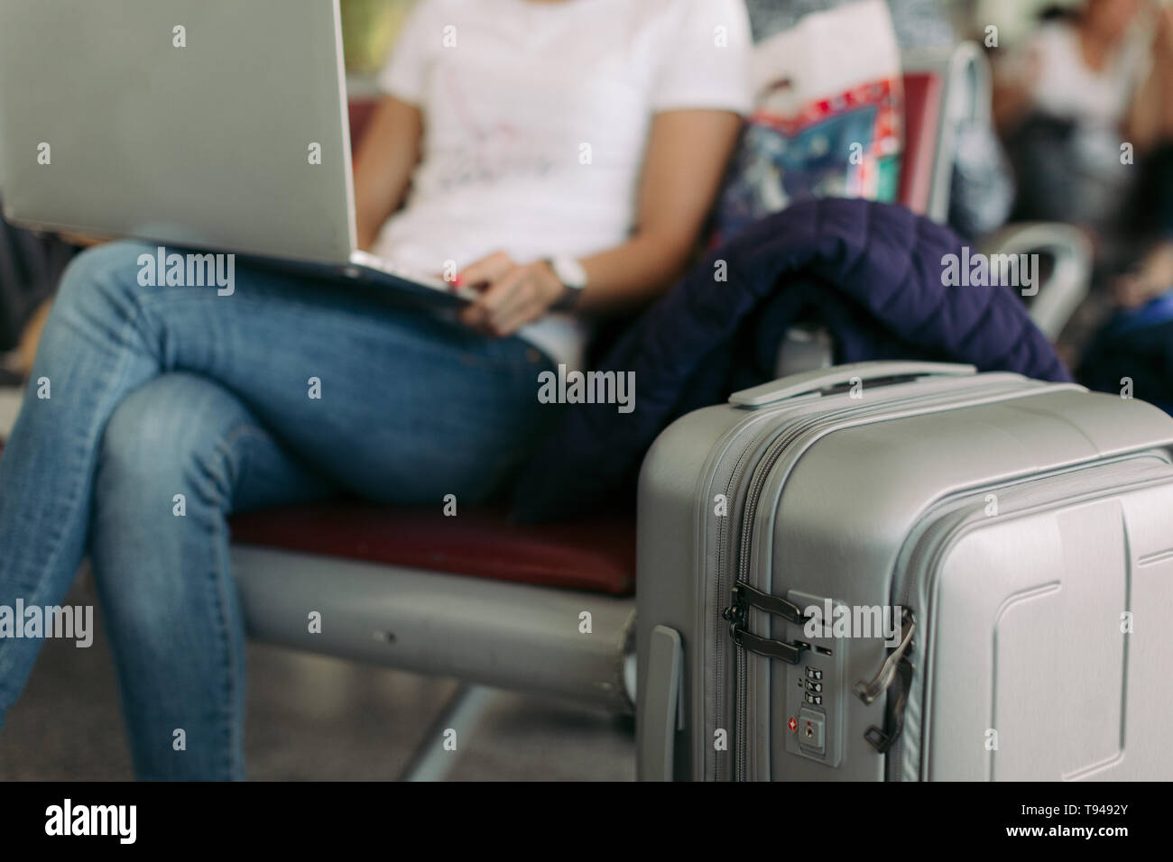 Young female passenger using laptop computer at airport while waiting ...