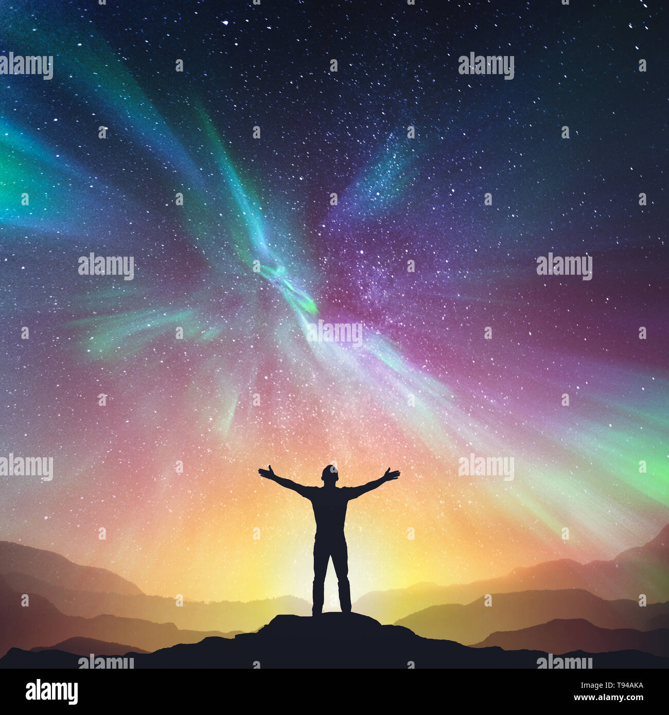 Silhouette of a standing young man with raised up arms on night stars ...