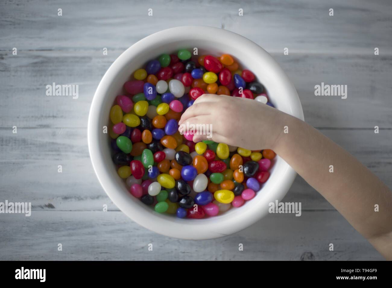 A child's hand picking up candy from a white plate Stock Photo - Alamy