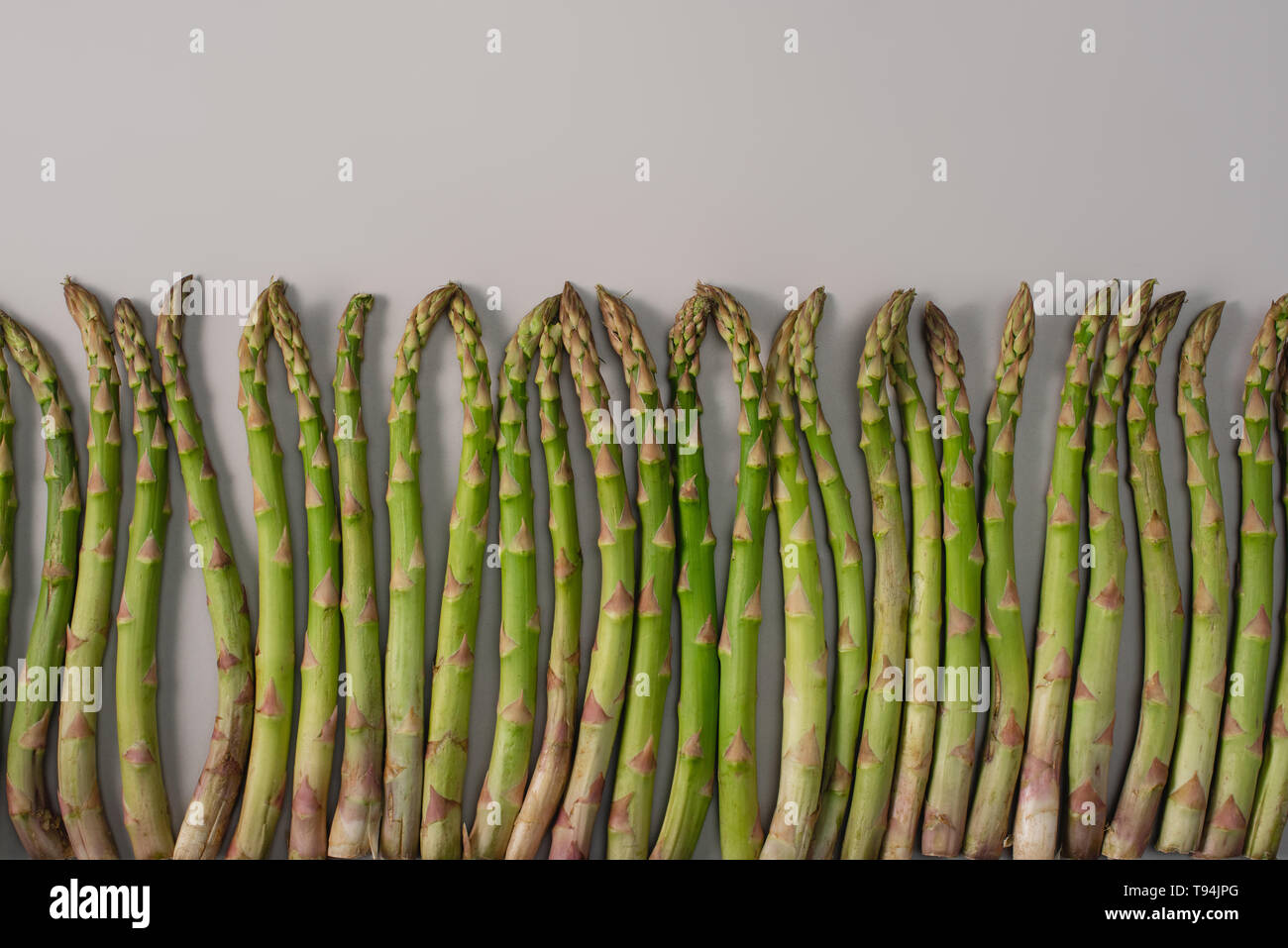 top view of green raw asparagus in row on grey background Stock Photo ...