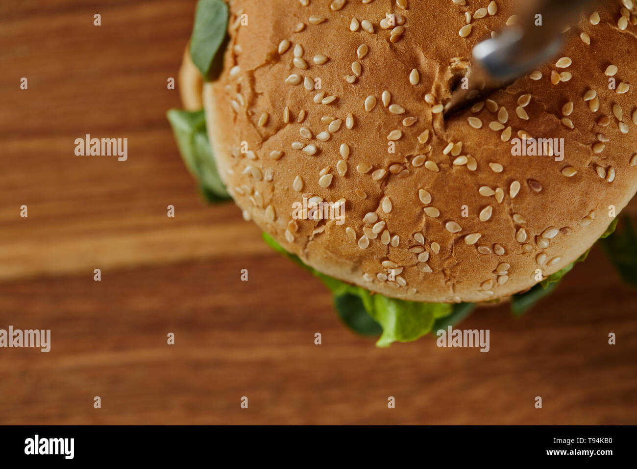 top view of knife in delicious burger on wooden chopping board Stock ...