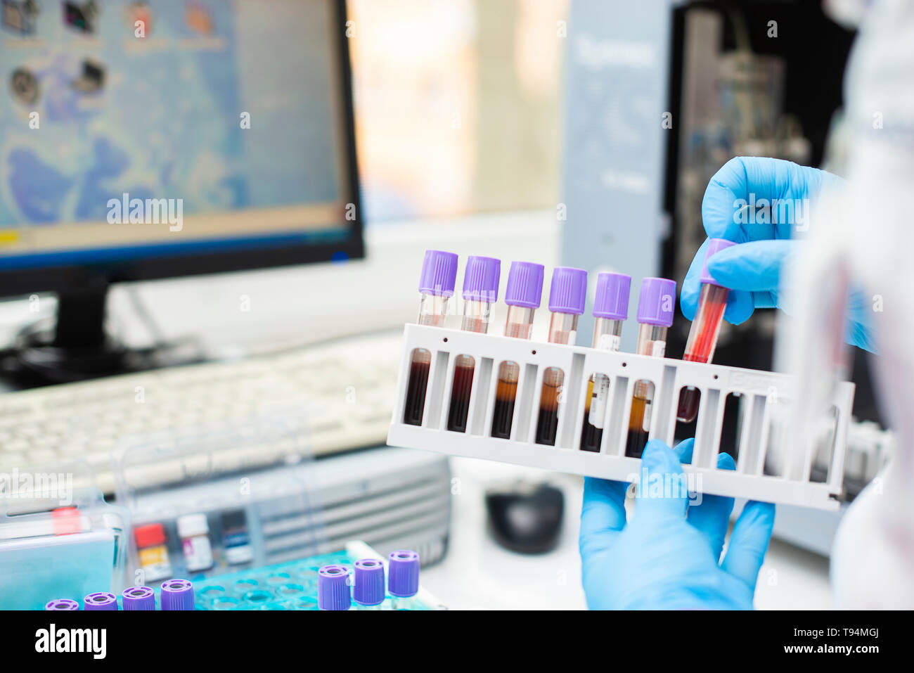 doctor hand taking a blood sample tube from a rack with machines of ...
