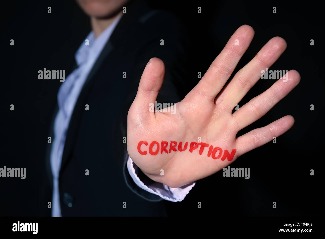 Woman with word CORRUPTION written on her palm against black background ...
