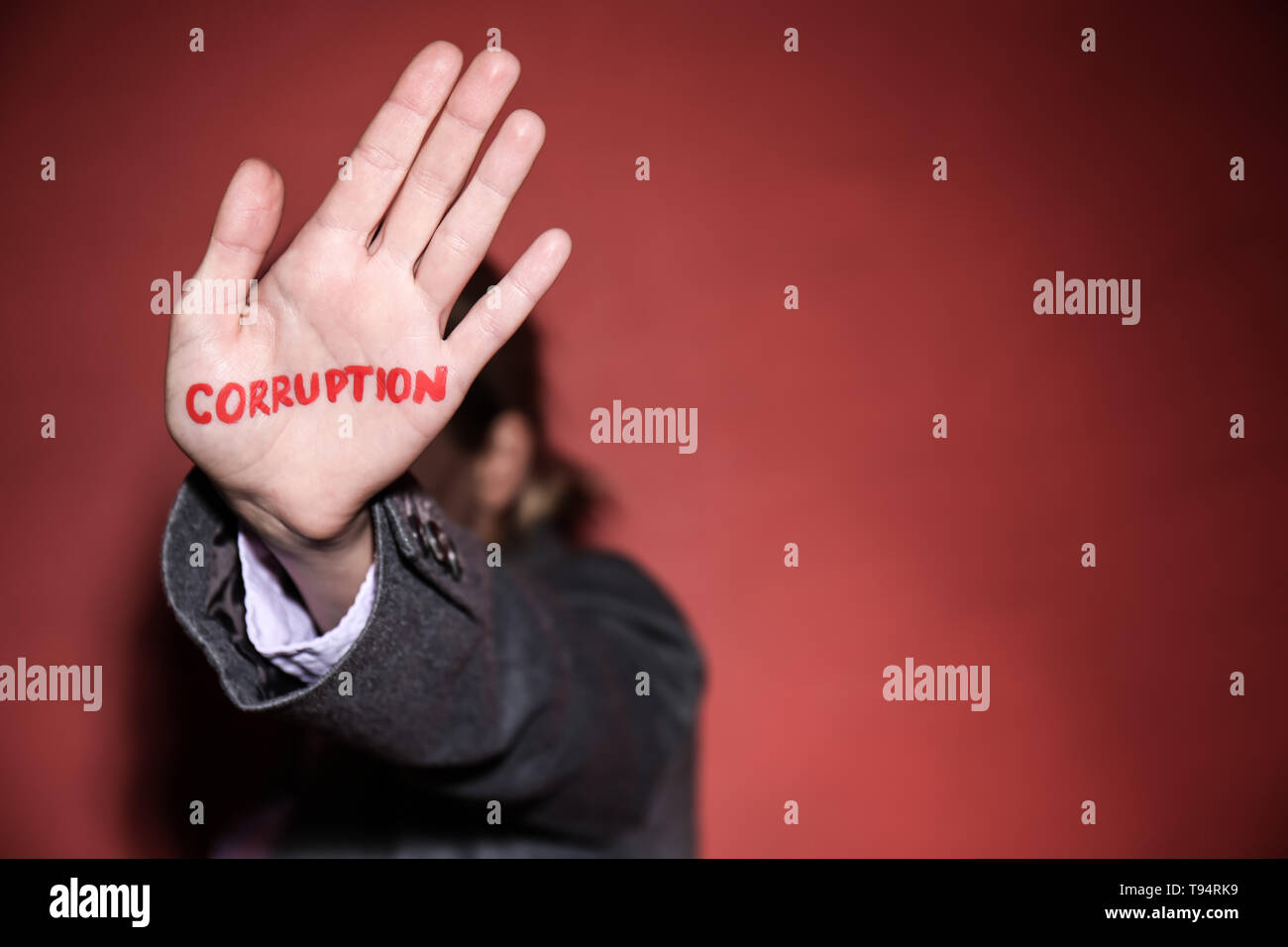 Woman with word CORRUPTION written on her palm against color background ...