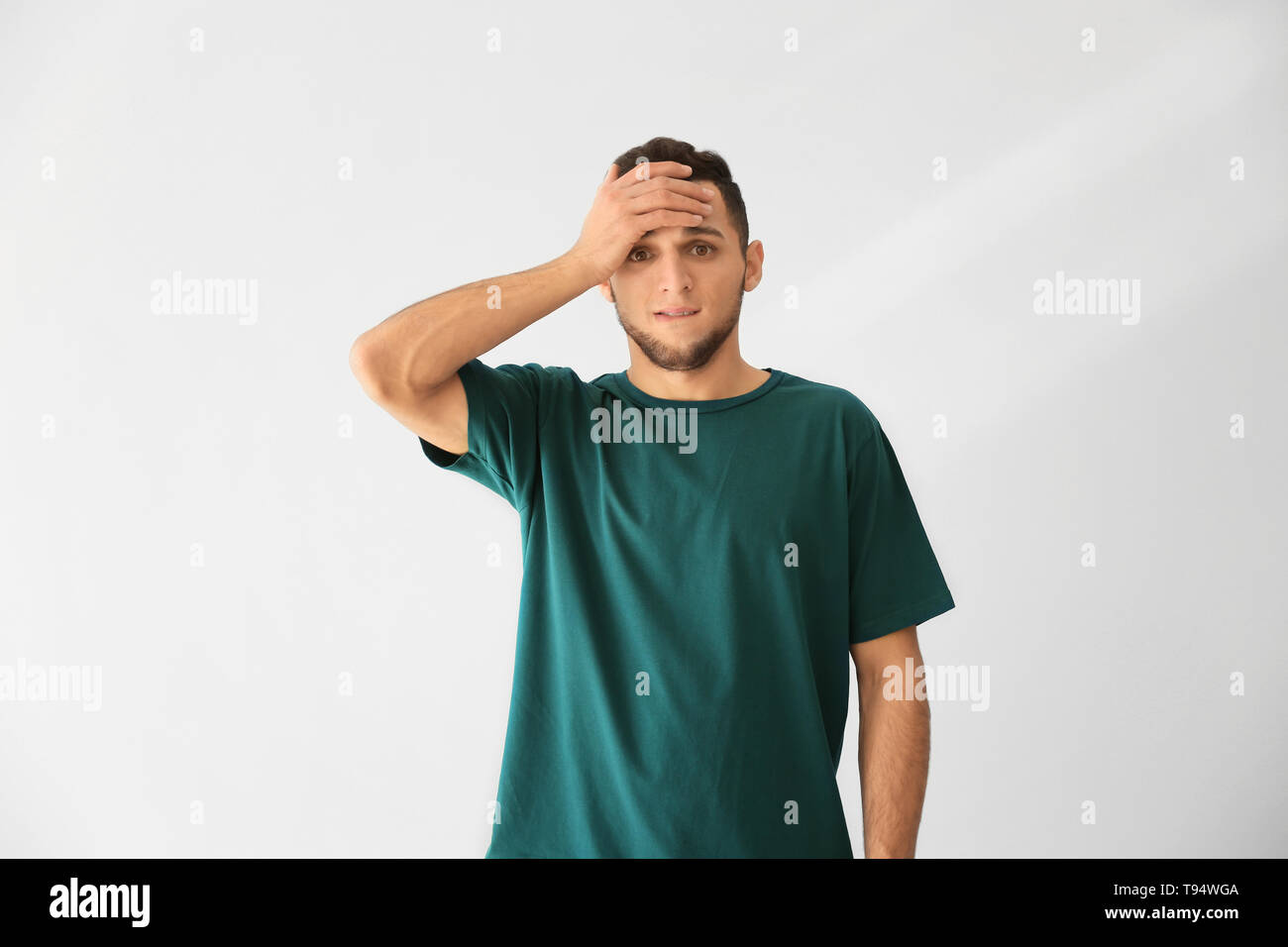 Emotional young man after making mistake on white background Stock ...