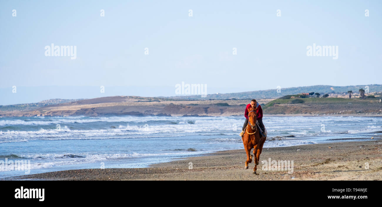 Ayia Eirini, Cyprus - 24 March, 2019: Man riding on a brown galloping ...